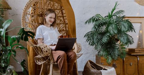 행복한 젊은 성인 여성이 이빨 미소를 짓고 집에서 고리 버들 의자에 앉아 현대 노트북 컴퓨터를 사용하고 사랑하는 방에서 침실에서 일한다 사진 Unsplash의 사무실