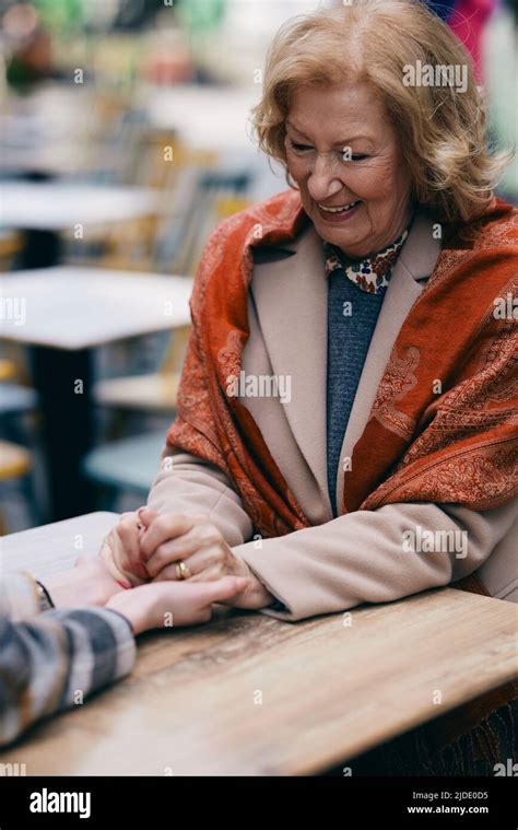 Grandmother With Her Granddaughter Is Sitting Outside Of The Cafe She Is Happy To Spend Time