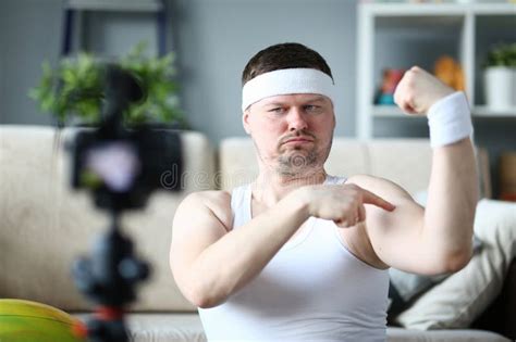 Energetic Joyful Male Blogger Measuring Bicep Size While Smiling And Updating Blog Stock Photo
