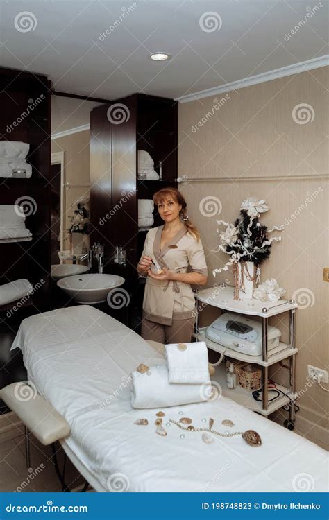 Female Massage Therapist Stands Near The Massage Table And Prepares To