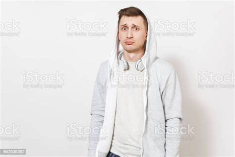 젊은 잘생긴 슬픈 화가 남성 학생 T셔츠와 흰색 배경에 고립 좌절 얼굴 목에 흰색 무선 헤드폰으로 후드와 함께 가벼운 운동복에