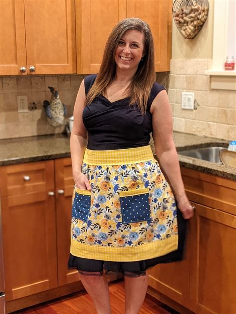 A Woman Standing In A Kitchen Wearing A Yellow And Blue Flowered Apron