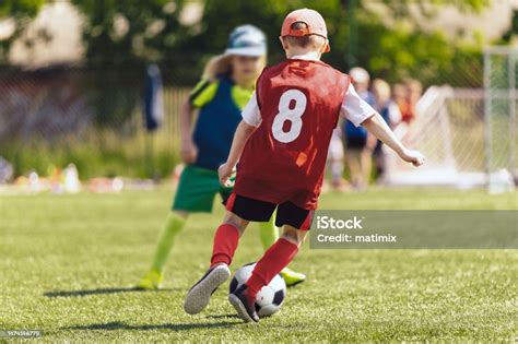 두 명의 남학생이 축구 경기를 합니다 스포티한 모자를 쓴 두 아이가 잔디밭에서 축구공을 차고 있다 여름 캠프에서 축구 훈련 수업