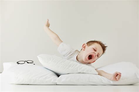 아이 소년은 아침에 편안한 침대에서 일어나 스트레칭 건강 관리와 좋은 아침 세계 개념 뻗어 하품 6 7 살에 대한 스톡 사진 및