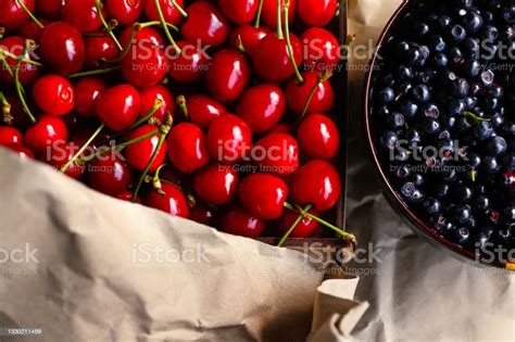 자른 상자 꼬리와 블루 베리 그릇과 어두운 빨간 달콤한 체리의 크레이프 공예 주름 오래된 종이 배경에 수확 및 작물 개념 유기농