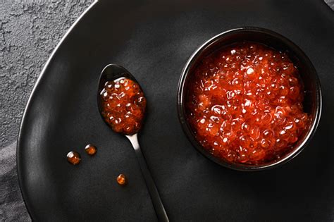 붉은 연어 캐비아 검은 색 어두운 콘크리트 배경에 검은 그릇에 맛있는 빨간 캐비아 복사 공간이 있는 위쪽 보기입니다 플랫 레이