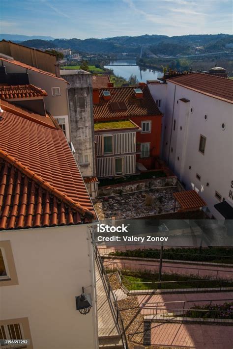 언덕 꼭대기 전망에서는 붉은 기와 지붕의 전통 건물과 현대적인 건축물이 조화를 이루고 있으며 부분적으로 흐린 하늘 아래 강과 먼 언덕이 내려다보입니다 0명에 대한 스톡 사진