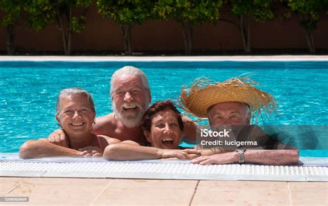 夏を楽しむスイミングプールの透明な水の中で一緒に4人の高齢者明るい太陽の下での幸福ターコイズブルーの水 4人のストックフォトや画像を多数ご