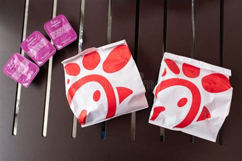 Two Chick Fil A Chicken Sandwiches In Bags With Logos And Sauce Packets