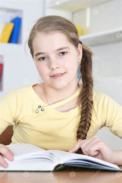 Colegiala Linda Que Se Sienta En La Tabla Y La Lectura Foto De Archivo