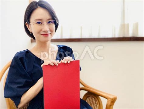 赤いバインダーを持って笑顔を向ける女性 No 27738706｜写真素材なら「写真ac」無料（フリー）ダウンロードok