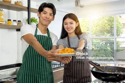 사랑 스러운 쾌활 한 행동에 앞치마에서 귀여운 행복 한 커플의 초상화 현대 부엌에서 샐러드의 성분으로 장식 테이블의 아침 식사와