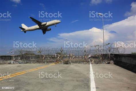 青い空を背景道路のブロックの有刺鉄線のフェンスでセキュリティと飛行機 まぶしいのストックフォトや画像を多数ご用意 まぶしい