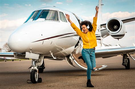 그녀는 공항 활주로에 주차 된 개인 제트기 옆에 헤드폰을 통해 재생 음악을 즐기는 어린 소녀 개인 비행기에 대한 스톡 사진 및 기타 이미지 Istock