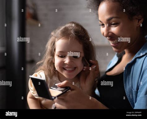 Delighted Ethnic Mother With Compact Spreading Powder On Face Of