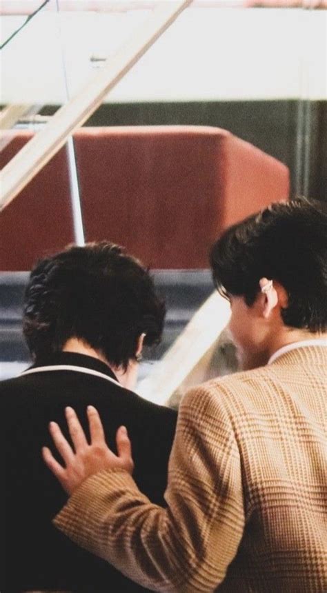 Two People Sitting Next To Each Other In Front Of An Escalator And One