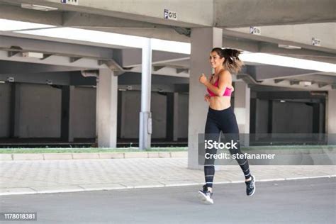 年輕女子與合適的身體跳躍和運行在灰色的背景運動服裝的女性模特在戶外鍛煉 照片檔及更多 一個人 照片 一個人 享受 人 Istock