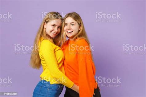 두 흥분 된 젊은 금발 쌍둥이 자매 여자에서 생생한 화려한 옷 서 찾고 카메라에 고립 된 파스텔 바이올렛 블루 벽 배경 사람들 가족 라이프 스타일 개념입니다 복사 공간을