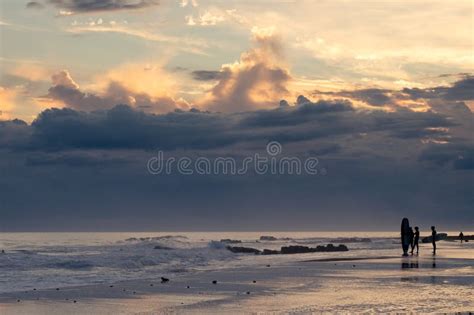A Group Of People Are Walking On The Beach At Sunset Stock Image
