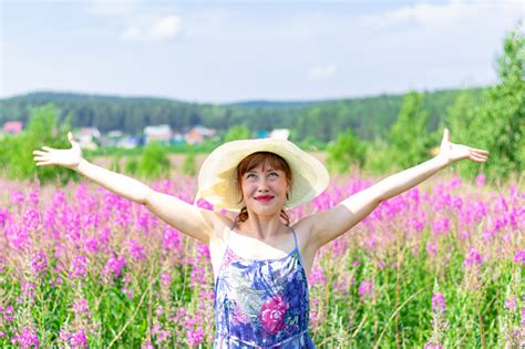 더운 여름날 초록색 숲과 푸른 하늘을 배경으로 밀짚 모자를 쓴 꽃밭에 있는 젊은 여성 봄에 대한 스톡 사진 및 기타 이미지 봄 여자 자홍색 Istock
