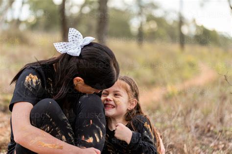 Image Of Happy Aboriginal Sisters Sitting Together Smiling In Bushland