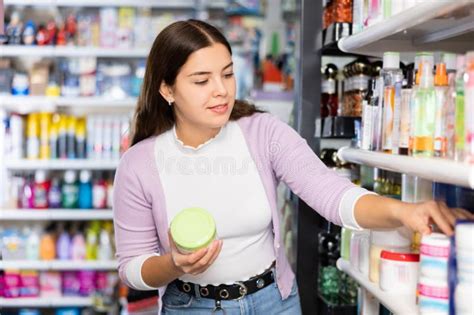 Portrait Of Cute Brunette Selecting Cream For Skincare In Beauty