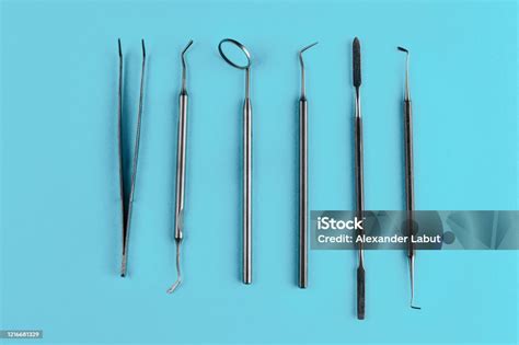 파란색 배경에 격리 된 금속 치과 의사 도구 및 장비 세트 강철은 입 거울 치주 탐색기 스케일러 핀셋 및 기타 악기를