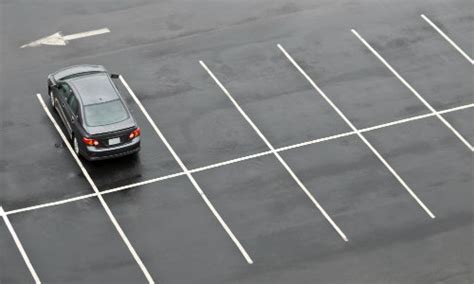 A Single Car Parked On An Asphalt Parking Lot Within Lanes