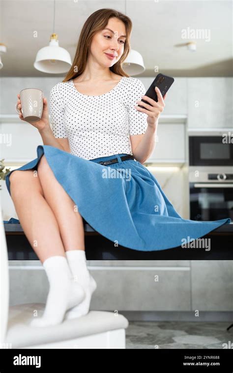 Girl In Flared Skirt Sitting On Dining Table And Put Her Legs On Chair