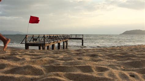 A Red Warning Flag Flies In The Wind On The Beach Storm At Sea