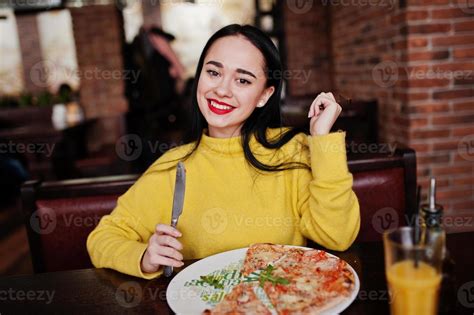 Funny Brunette Girl In Yellow Sweater Eating Pizza At Restaurant