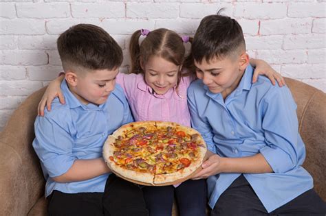 두 소년과 소녀 큰 이탈리아 피자를 들고 소파에 앉아 즐겁게 피자를보고 개념 10 11세에 대한 스톡 사진 및 기타 이미지 10 11세 2명 6 7 살 Istock