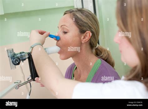 Woman Undergoing A Lung Function Test Using A Spirometer That Measures The Maximum Rate At Which