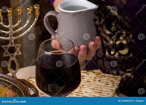 A Woman At A Table Laid For A Passover Seder Holds A Pitcher Of Salt