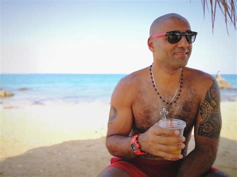 Premium Photo Smiling Shirtless Man Sitting With Drink At Beach