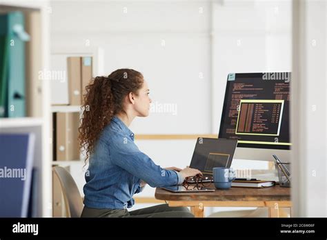 Side View Portrait Of Female IT Developer Using Computer While Coding In Modern White Office