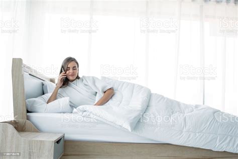 깨어난 후 웃는 얼굴로 침대에서 스마트 폰을 말하는 여성 가정의 방에 대한 스톡 사진 및 기타 이미지 가정의 방 개념