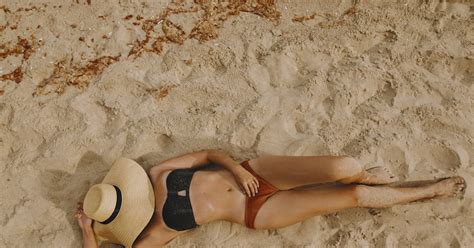 여름 방학 및 여행 모자를 들고 해변에 누워 있는 소녀 밀짚모자를 쓴 세련된 젊은 여성이 바다 근처의 모래 해변에서 휴식을 취하고 있다 평온한 상위 뷰 사진