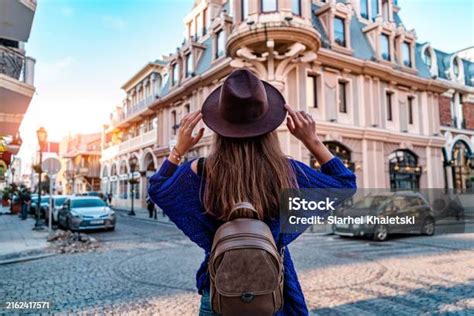 캐주얼 스타일리시한 패셔너블한 힙스터 여행자 모자와 갈색 배낭을 들고 혼자 유럽 도시를 걷고 있는 여자 여행 주제에 대한 스톡