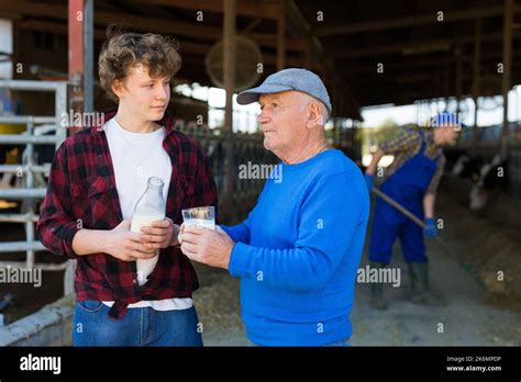 Portrait Of An Elderly Farmer With His Grandson Holding Bottle Of Milk