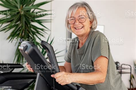 사람들은 스포츠 개념입니다 쾌활한 선배 여자는 집 테라스에서 고정식 자전거를 타고 달리기 위해 운동을 한다 노인 활동적인 여성과
