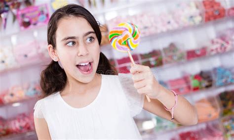 Girl Holding Sweet Colored Lollipop On Stick In Candy Shop Stock Image