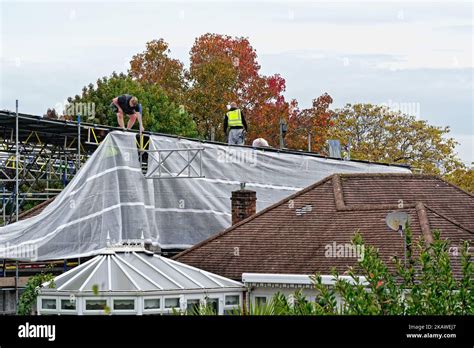 Scaffolders Erecting Scaffold On A Suburban Bungalow Prior To Building