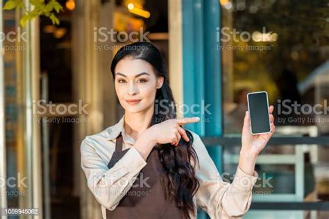 스마트폰 카페 근처 빈 화면에 가리키는 앞치마에서 아름 다운 웨이트리스 보여주기에 대한 스톡 사진 및 기타 이미지 보여주기