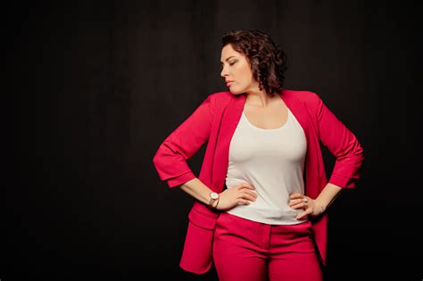 빨간 양복을 입은 한 여성이 허리띠에 손을 얹고 검은 색 배경으로 고개를 돌린다 여유 공간 검은 배경에 매력적인 사업가 복사 공간 갈색 머리에 대한 스톡 사진 및 기타