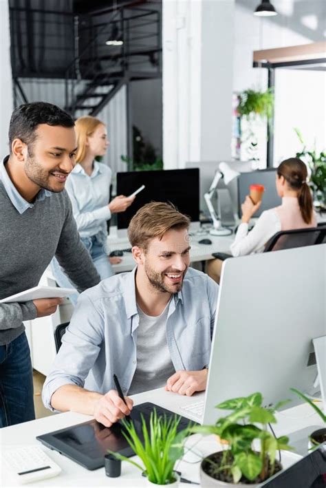 Multiethnic Colleagues With Laptop And Coffee Sitting And Looking At