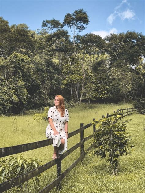 A Woman In A White Dress Leaning On A Fence