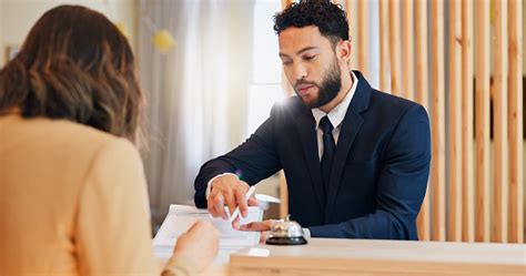 호텔 정보 및 남자와 함께 책상에있는 여성 환대를위한 체크인 및 친절한 리셉션 서비스 서류 작업 등록 및 숙박 예약 또는 여행을 위한 카운터에서 고객과 접수 담당자 호텔에