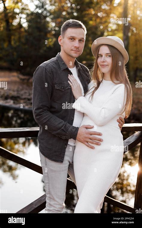 Happy stylish pregnant woman and man hugs, kiss, touches belly and listen baby's kicks, walk ...