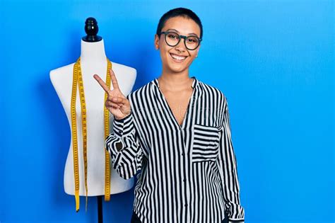 Beautiful Hispanic Woman With Short Hair Standing By Manikin Smiling